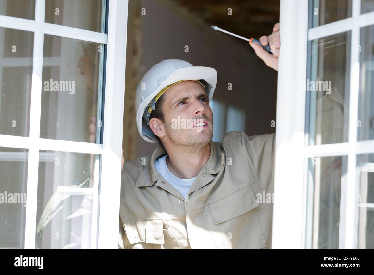 construction worker looking at window in house Stock Photo - Alamy