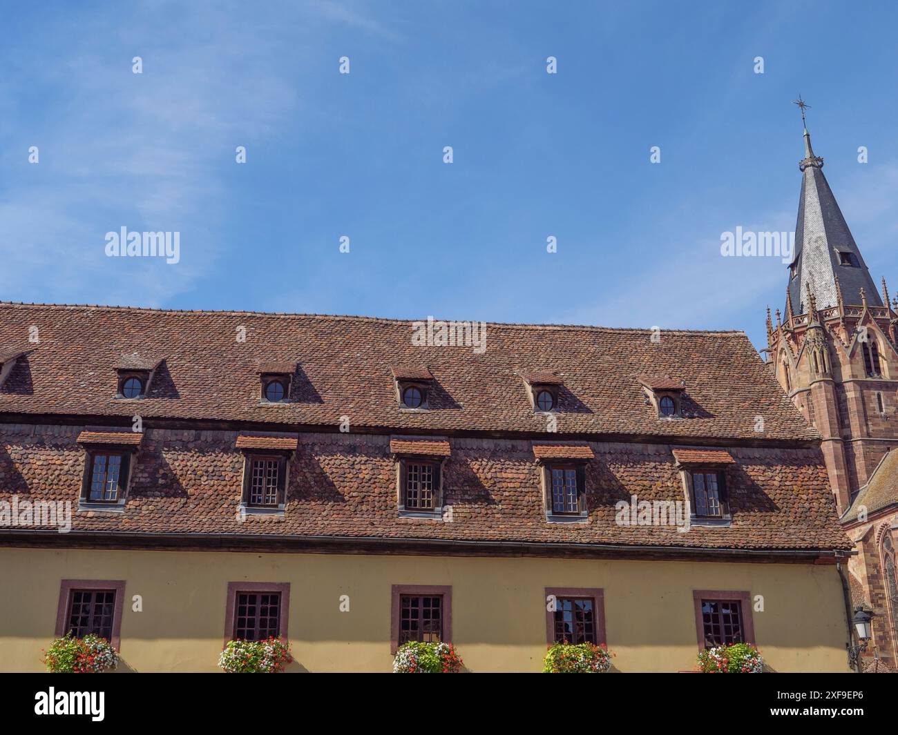 House with a sloping tiled roof and several small windows, next to it a ...