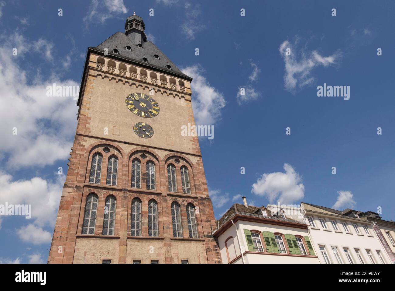 Historic church tower with clock and classical buildings under a blue ...