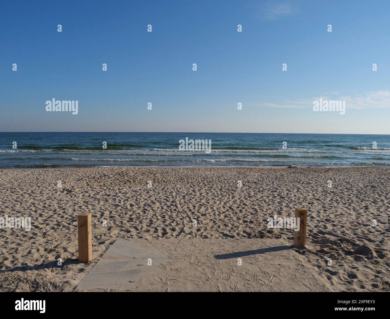 Clear view of the beach and the sea with two wooden posts and ...