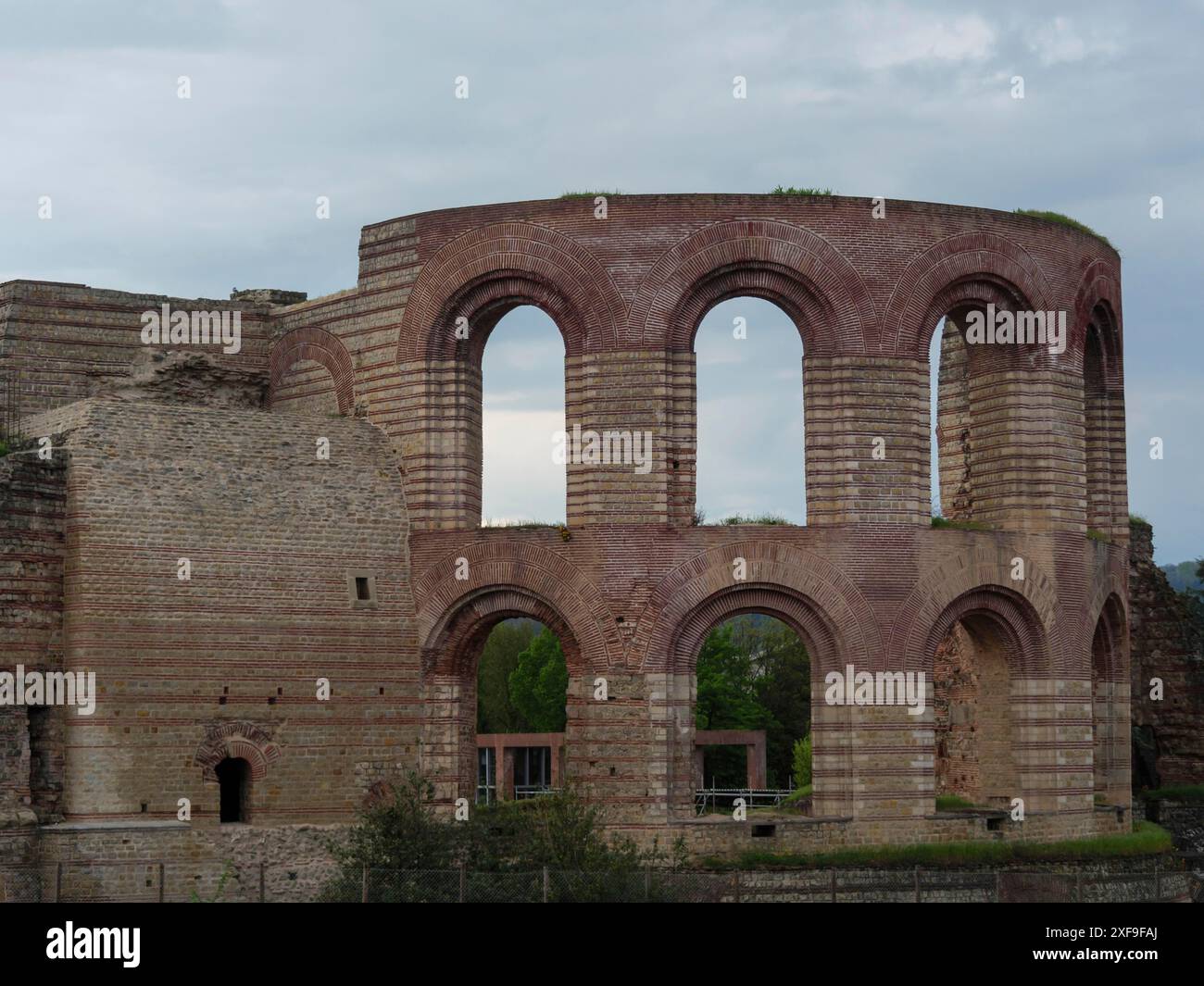 Roman ruins with large stone arches and overgrown grass that tell an ...