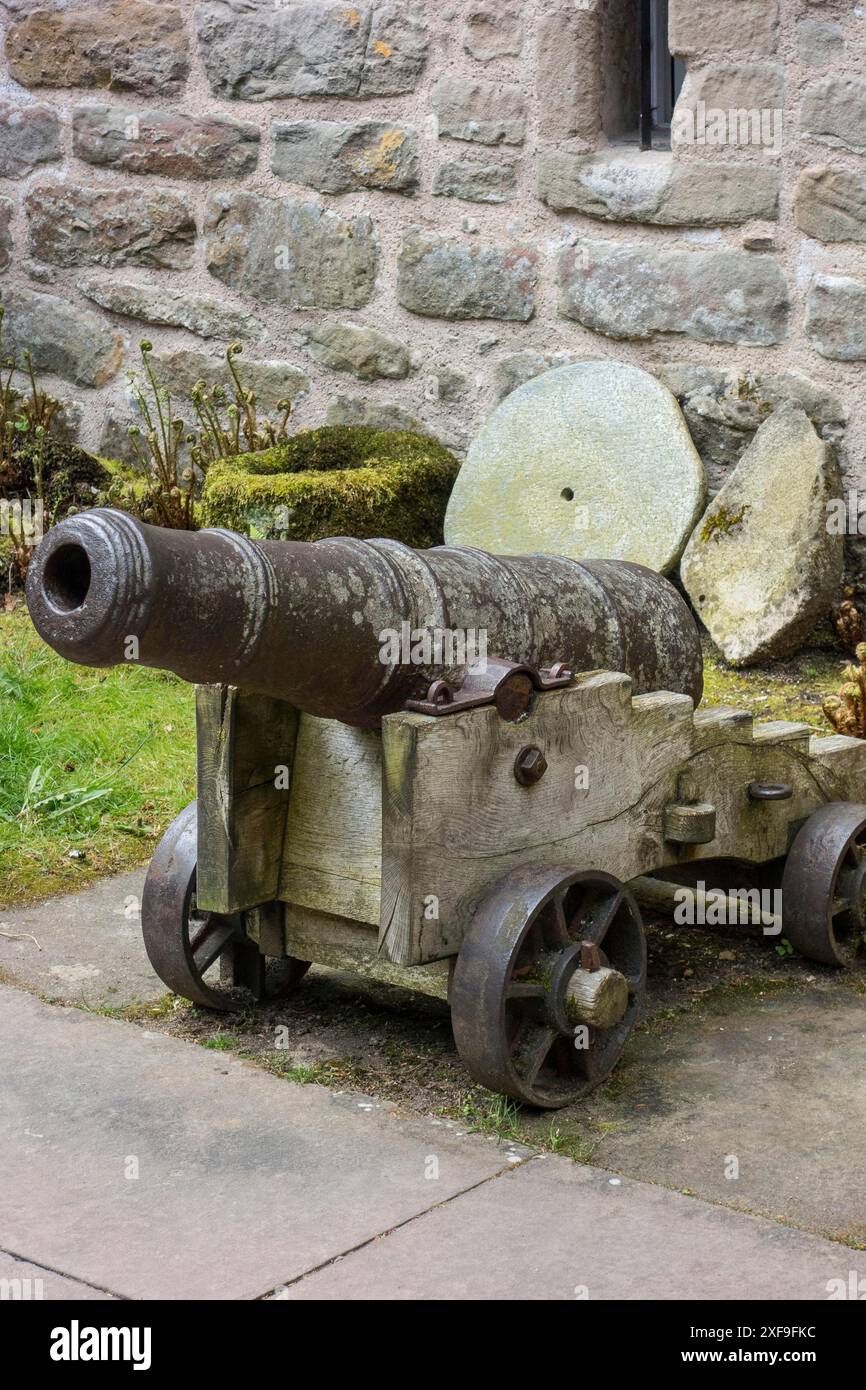 Old cannon on wheels in front of a stone wall in an outdoor area ...
