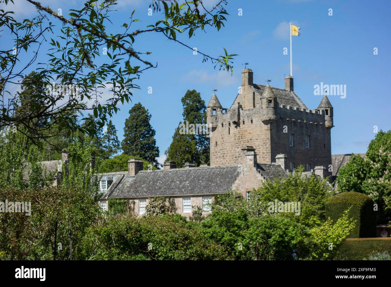 Historic castle with towers and open flag, surrounded by trees and a ...