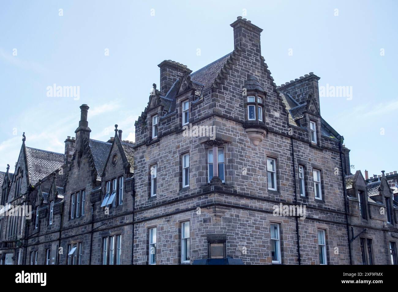 Historic stone building with slate roofs and windows under a blue sky ...