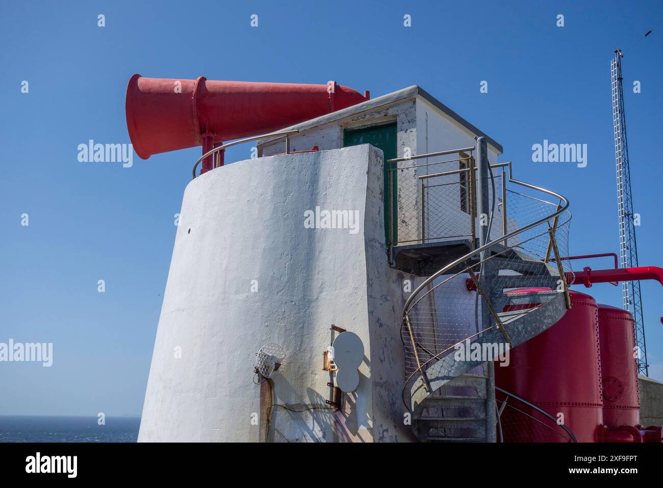 White lighthouse with a red structure and spiral staircase, under a ...