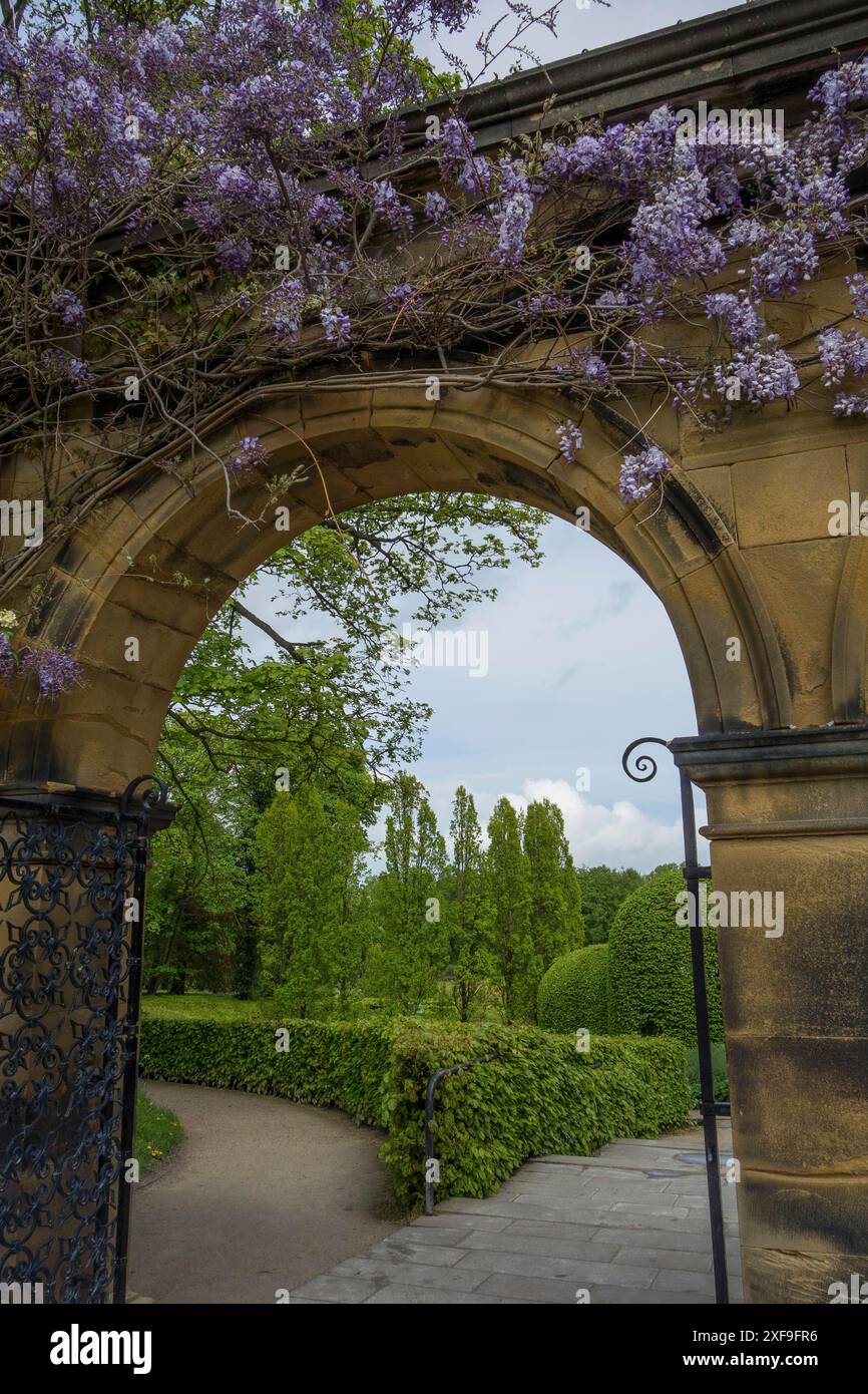 Stone archway with flowering plants and view of manicured garden path ...