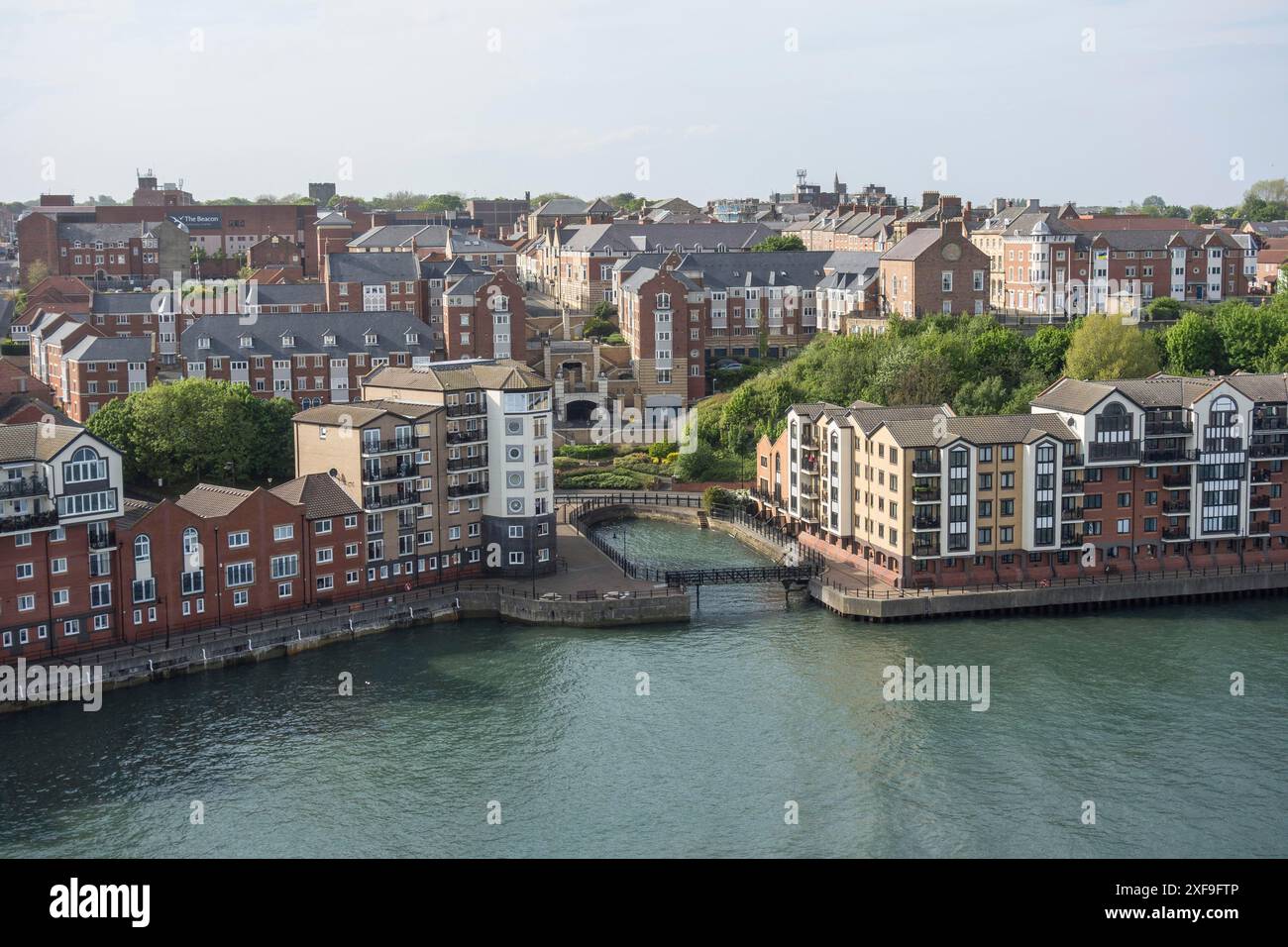 Modern residential complexes along a riverbank, surrounded by green ...