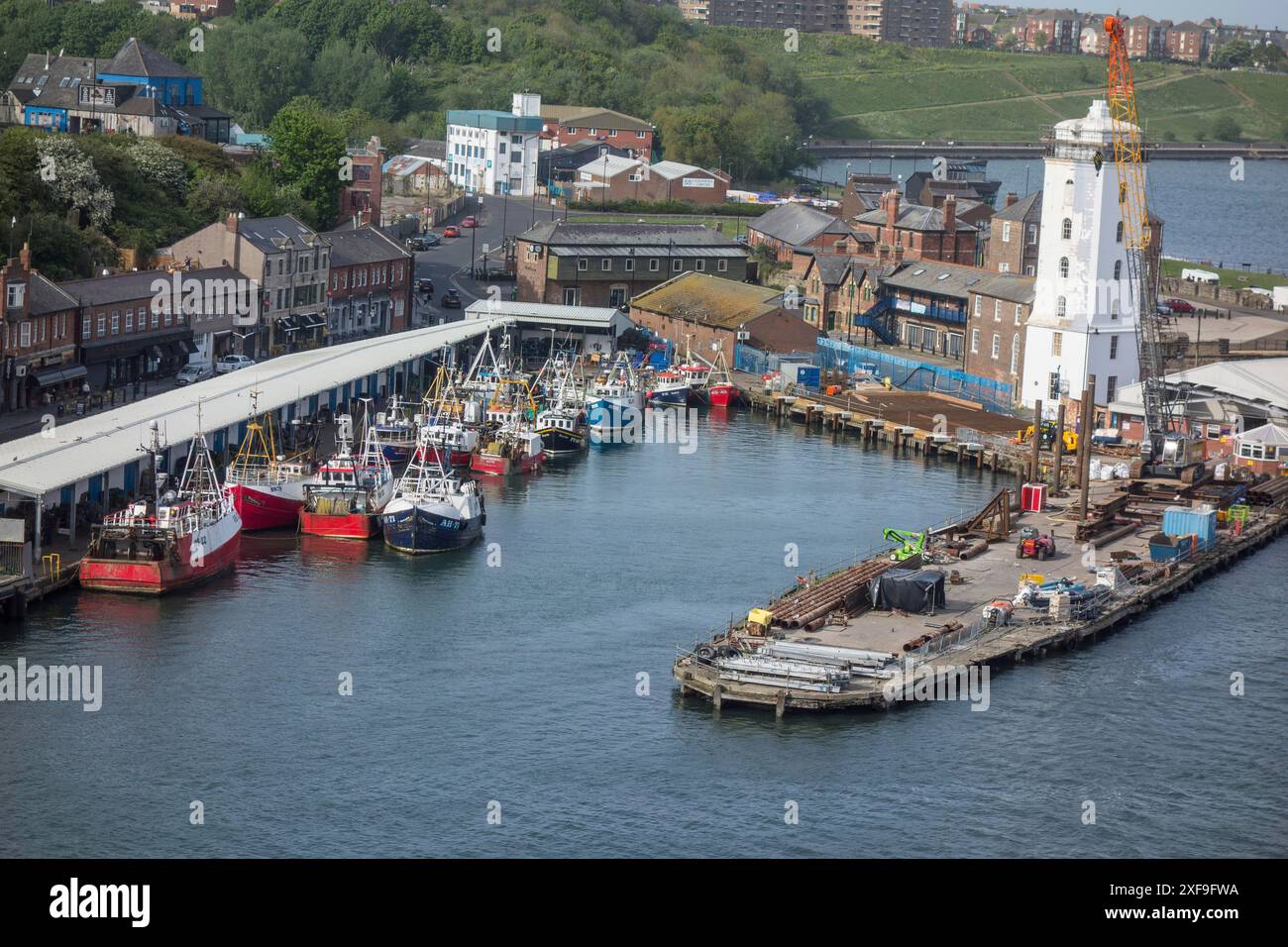 Harbour area with many fishing boats and warehouses, industrial cranes ...