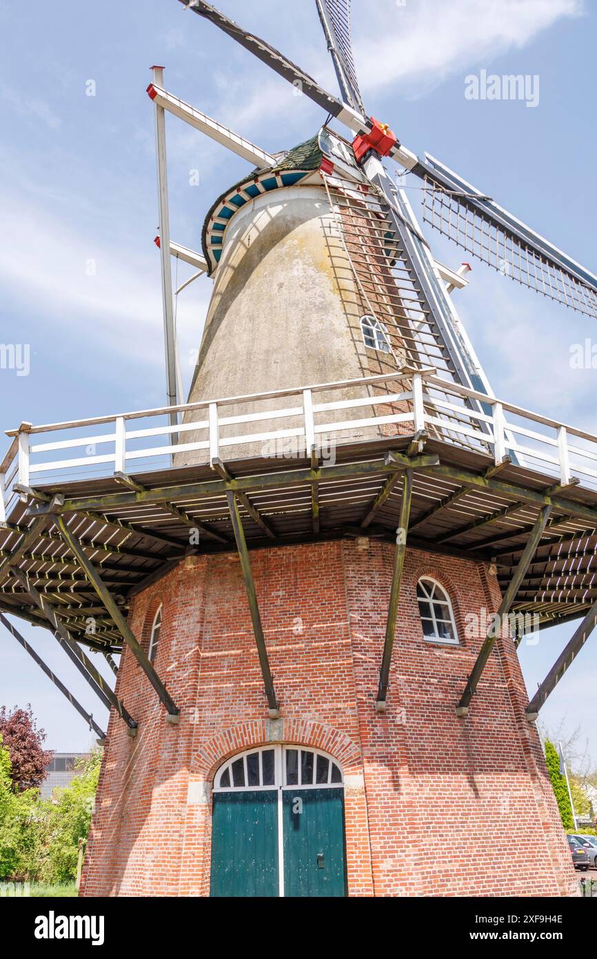 Old brick windmill with traditional wooden structure under a blue sky ...