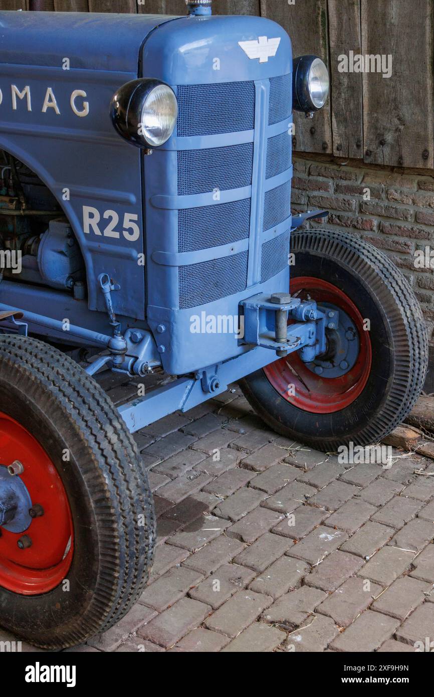 A blue Hanomag tractor with red wheels stands on paved ground in front ...