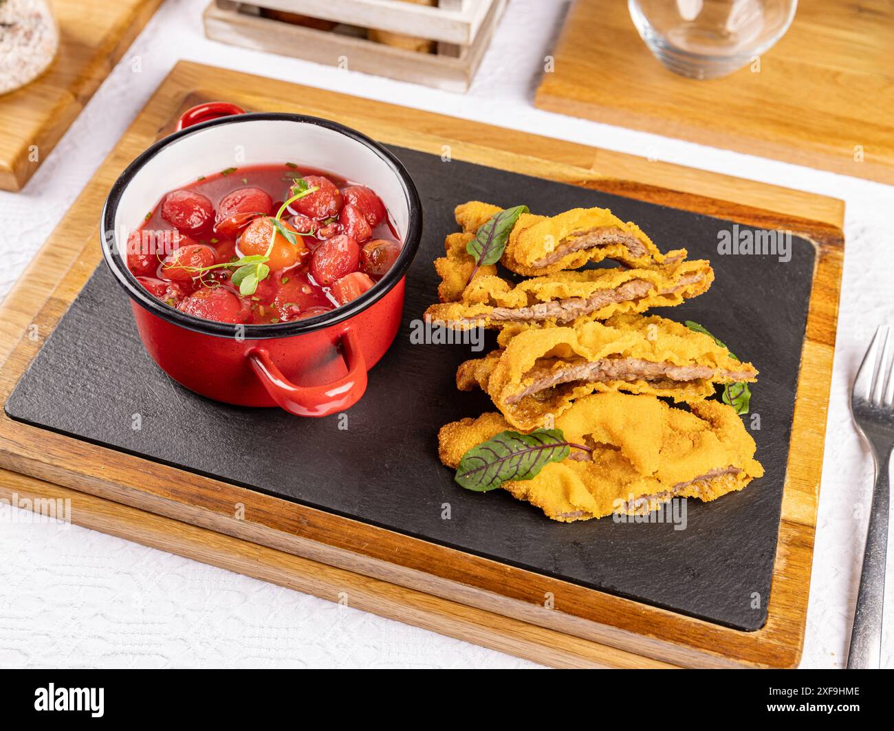 Breaded escalope of meat with tomato salad served on black slate tray ...