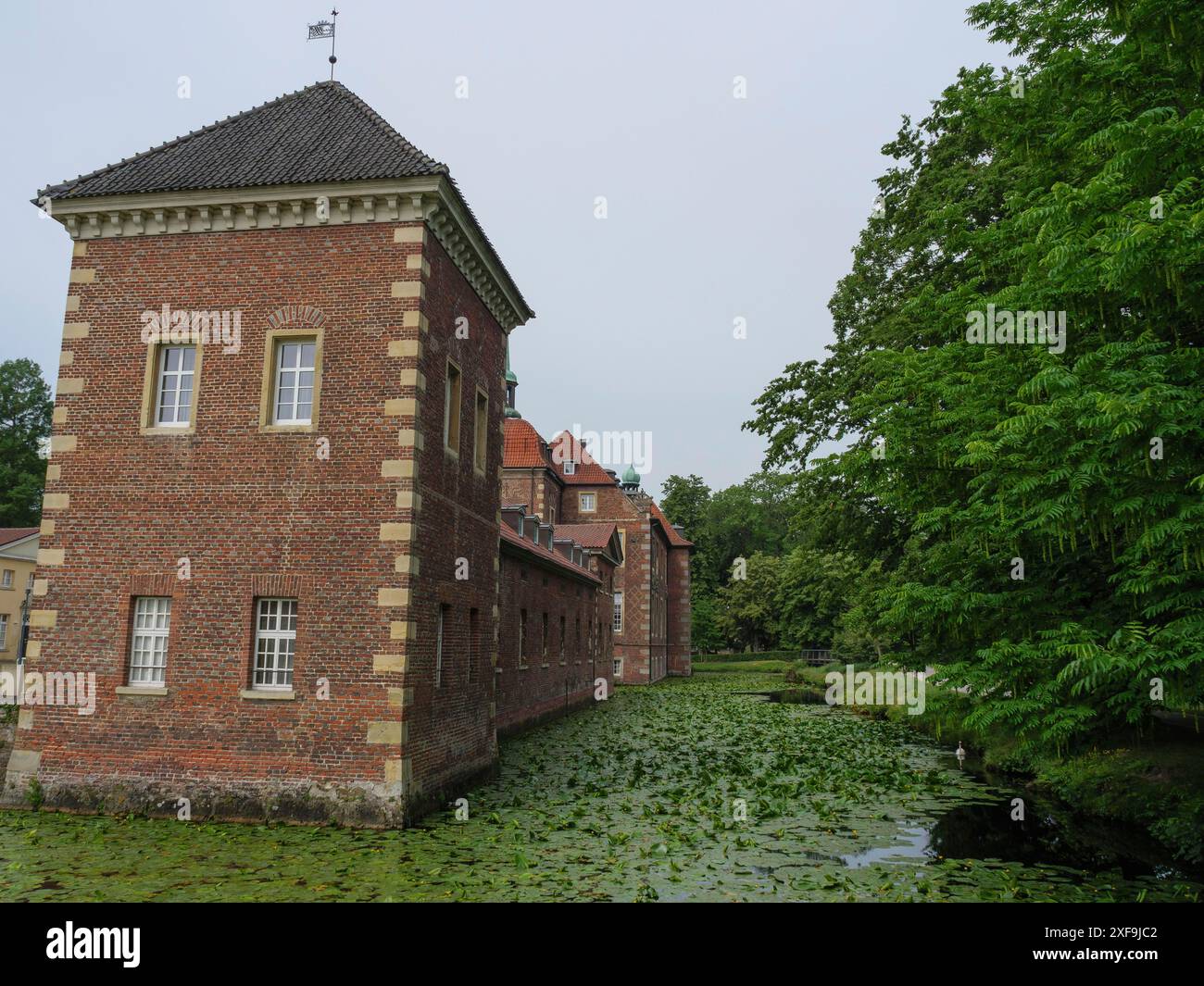 Historic brick castle with moat surrounded by green vegetation, Velen ...