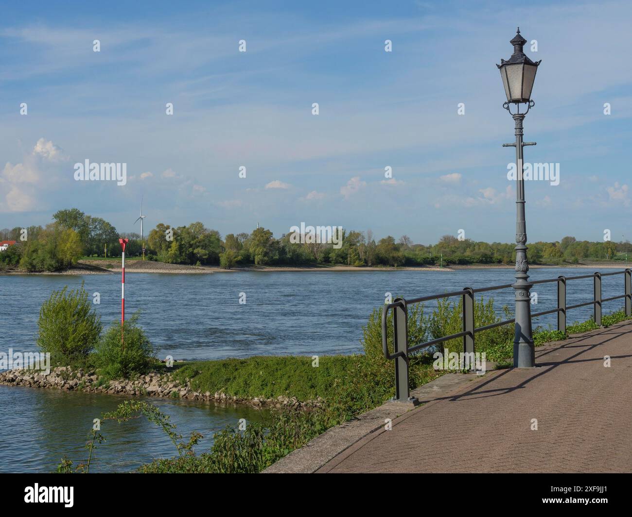 Riverside promenade with a lantern and a railing under a sunny blue sky ...
