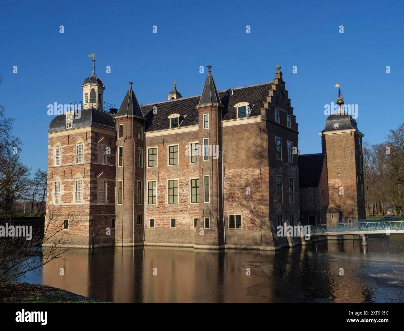 An old brick castle with towers and windows, surrounded by a moat under ...