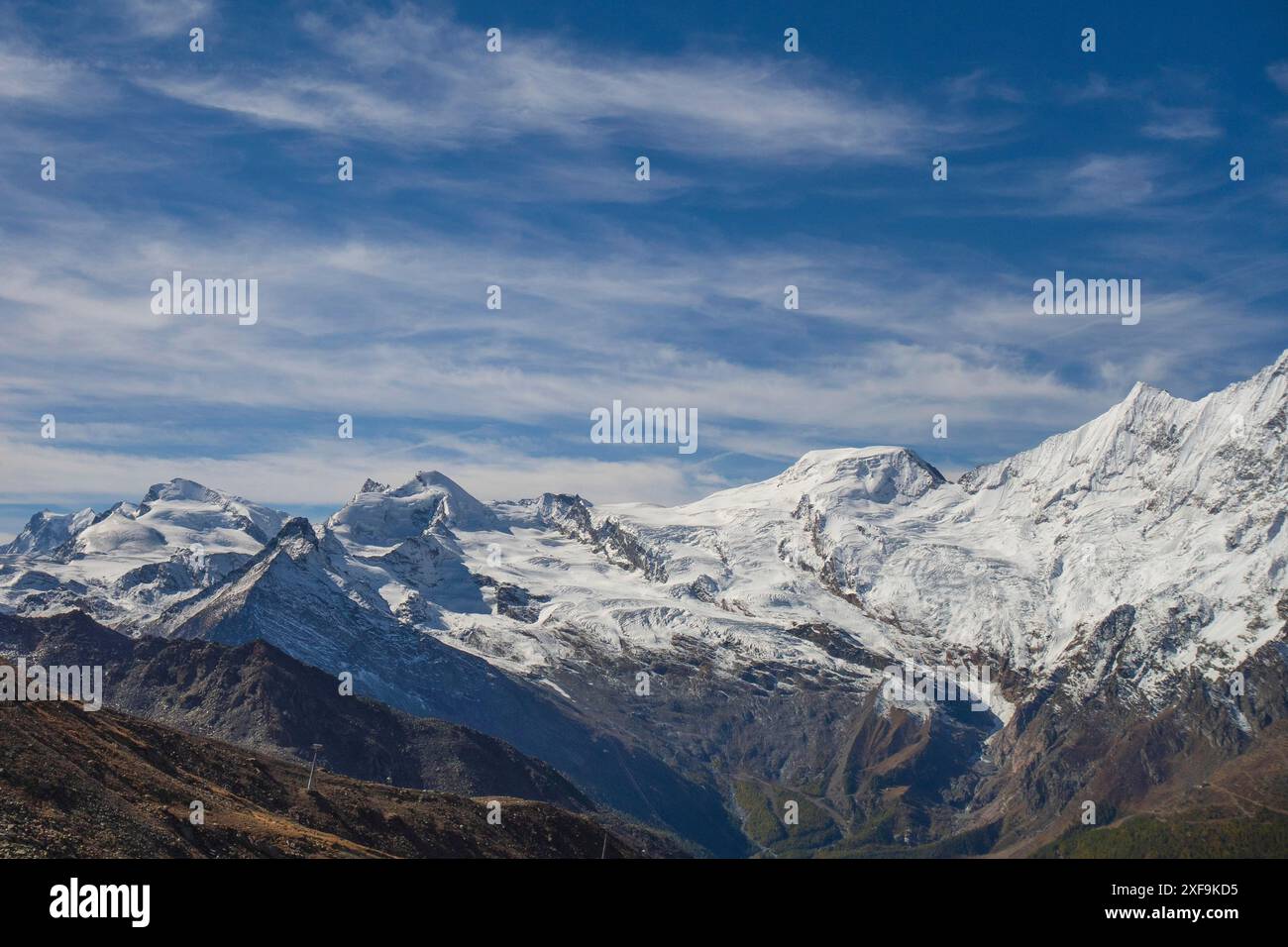 Vast snow-covered mountains under a blue sky with light clouds, saas ...