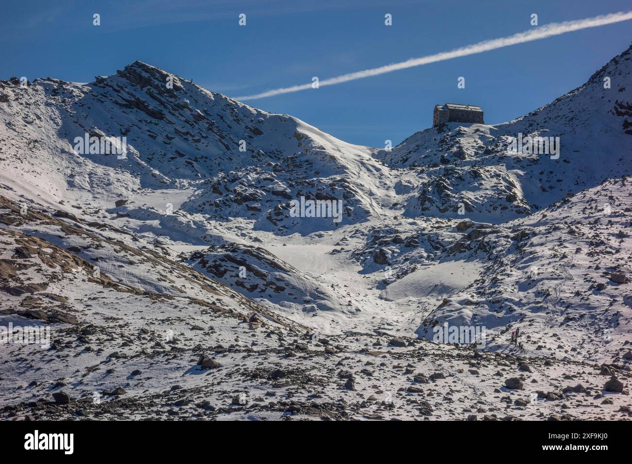 Summit area with snow-covered slopes and lonely hut and clear blue sky ...