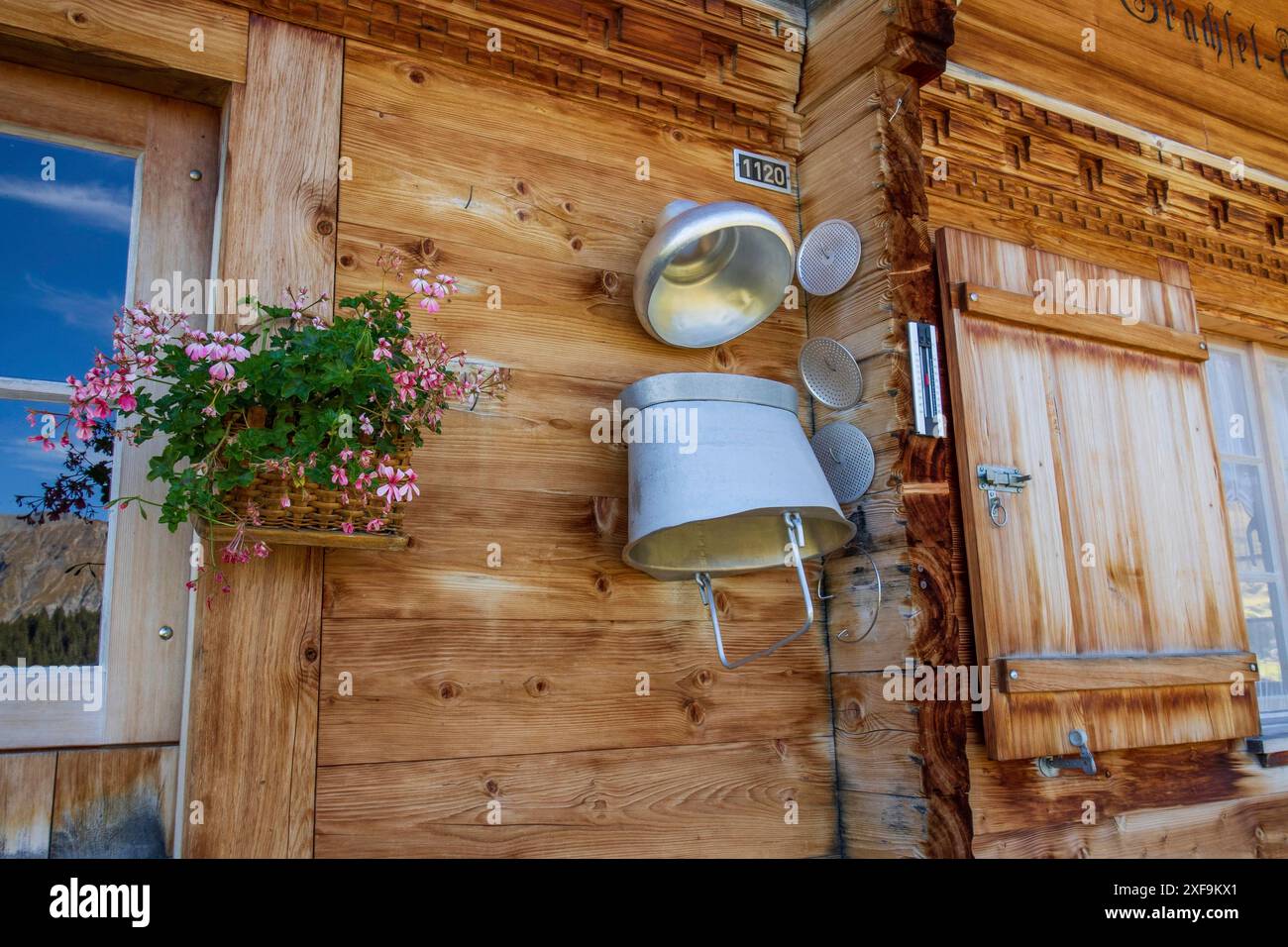 A rustic wooden wall with a window, a flower box and a decorative milk ...