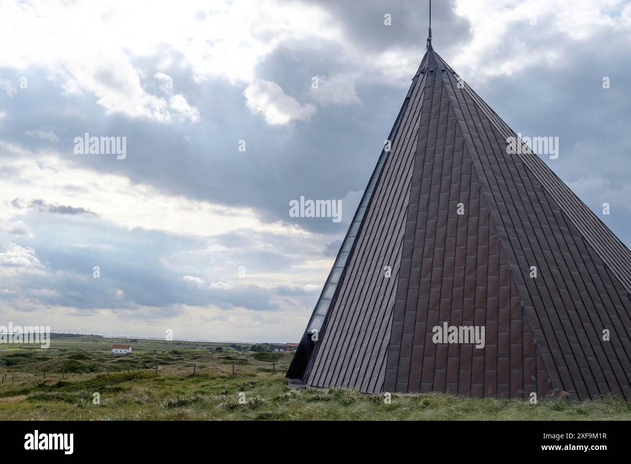 A pyramid-shaped building in an open landscape under a cloudy sky ...