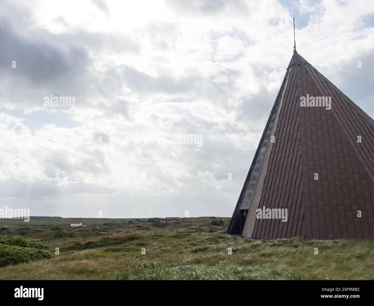 A pyramid-shaped building stands in an open grassy landscape under a ...
