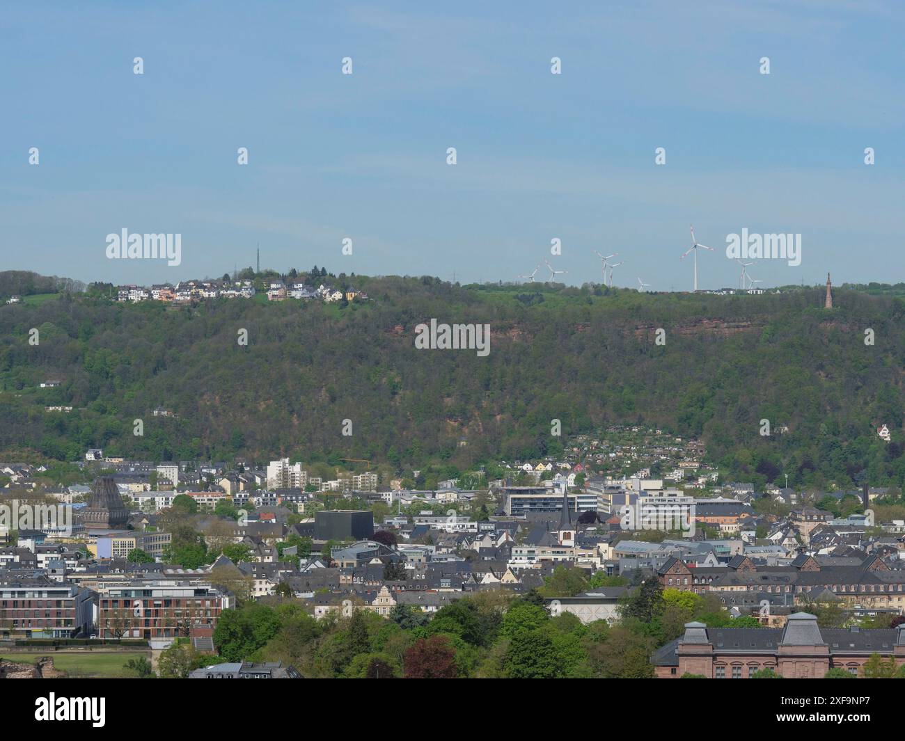 Urban landscape with modern buildings in the foreground and wooded ...