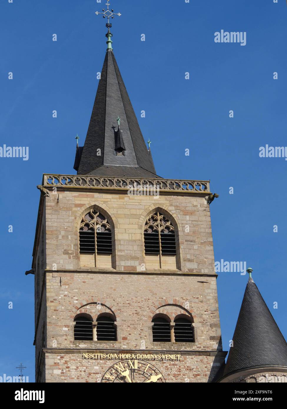 Close-up of a historic church tower with bells in front of a clear blue ...