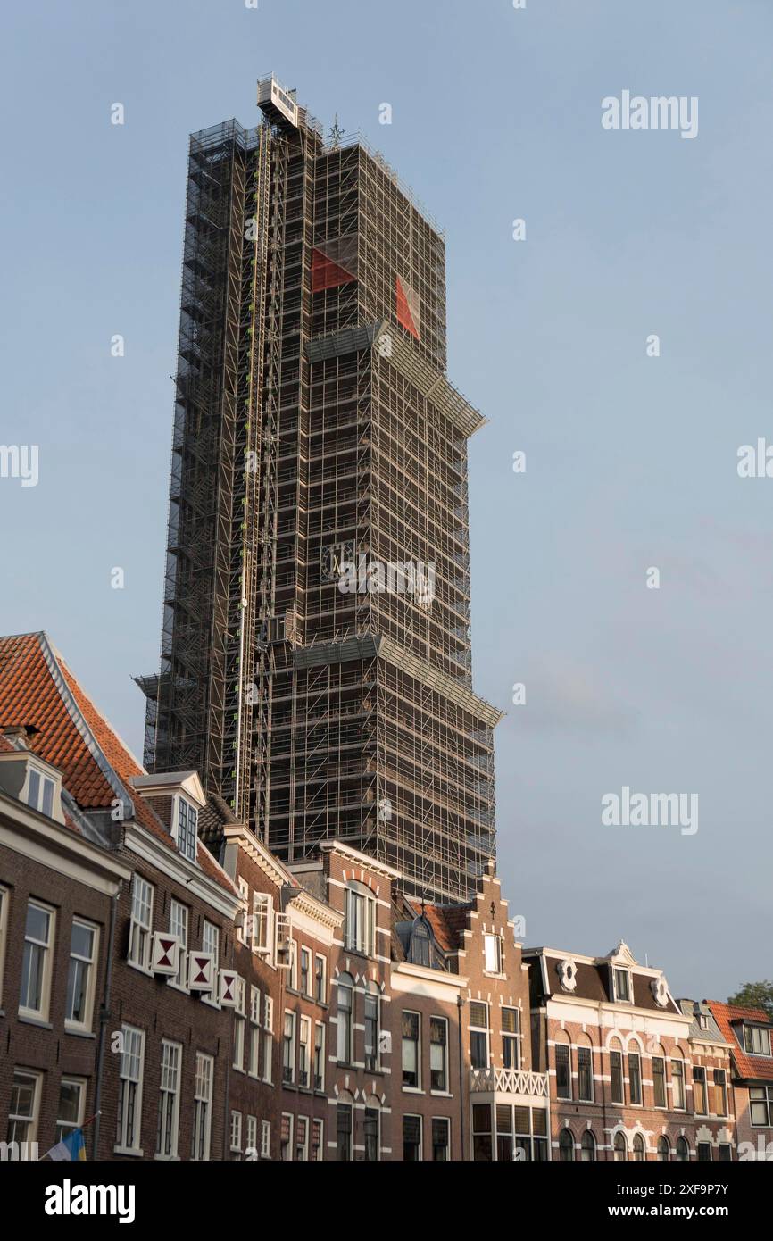 A high-rise building with scaffolding surrounded by traditional brick ...