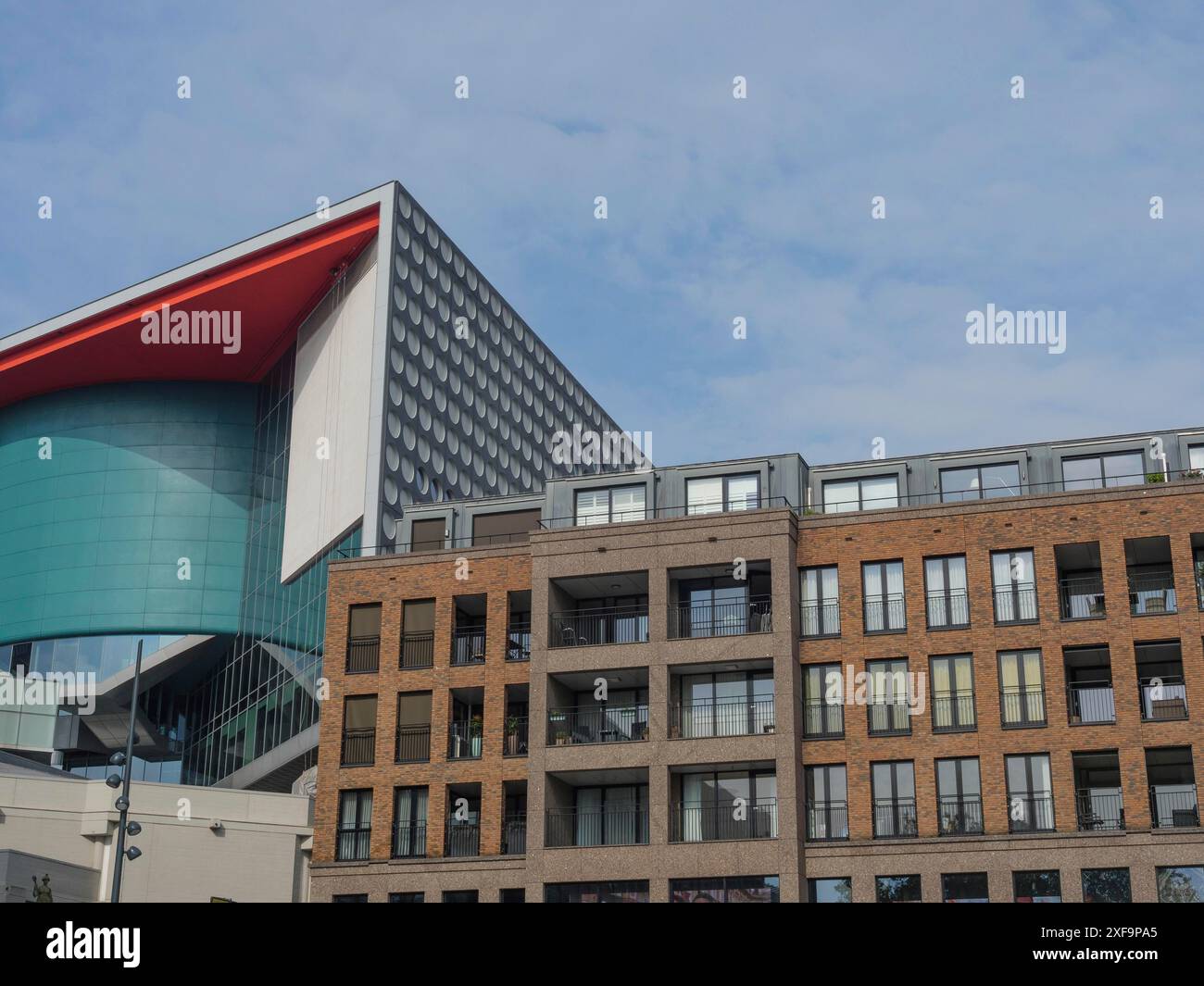 Modern architecture with a striking red roof next to a brick building ...