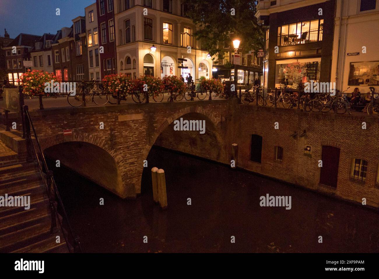 Illuminated bridge at night over a quiet canal, surrounded by historic ...