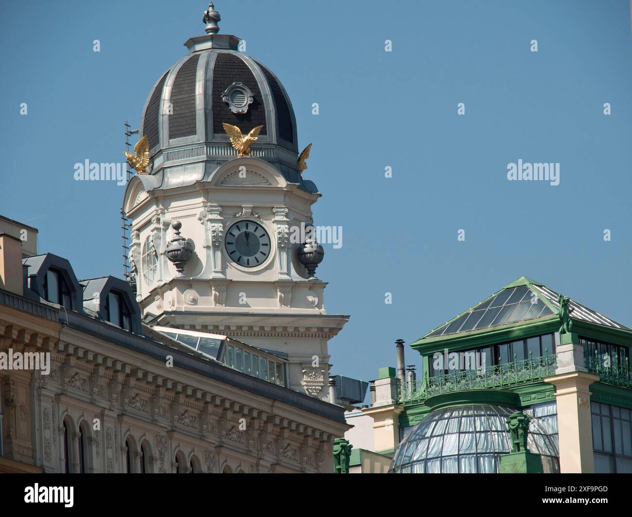 Historic clock tower next to modern buildings under a clear, sunny sky ...