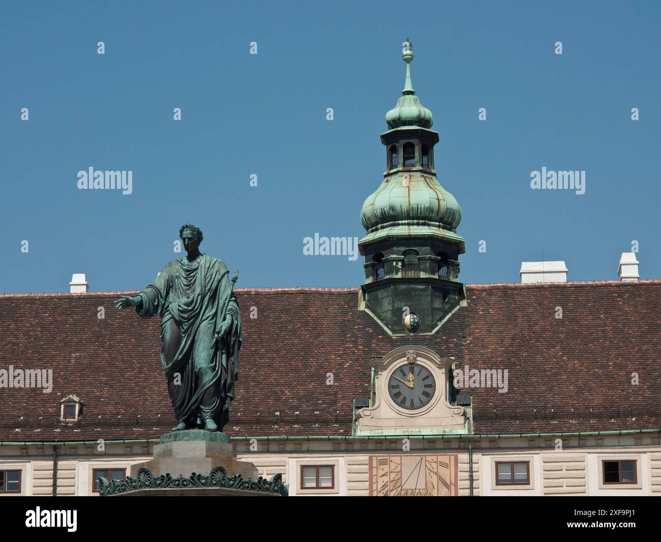 Statue in front of a building with a spire and a clock under a clear ...