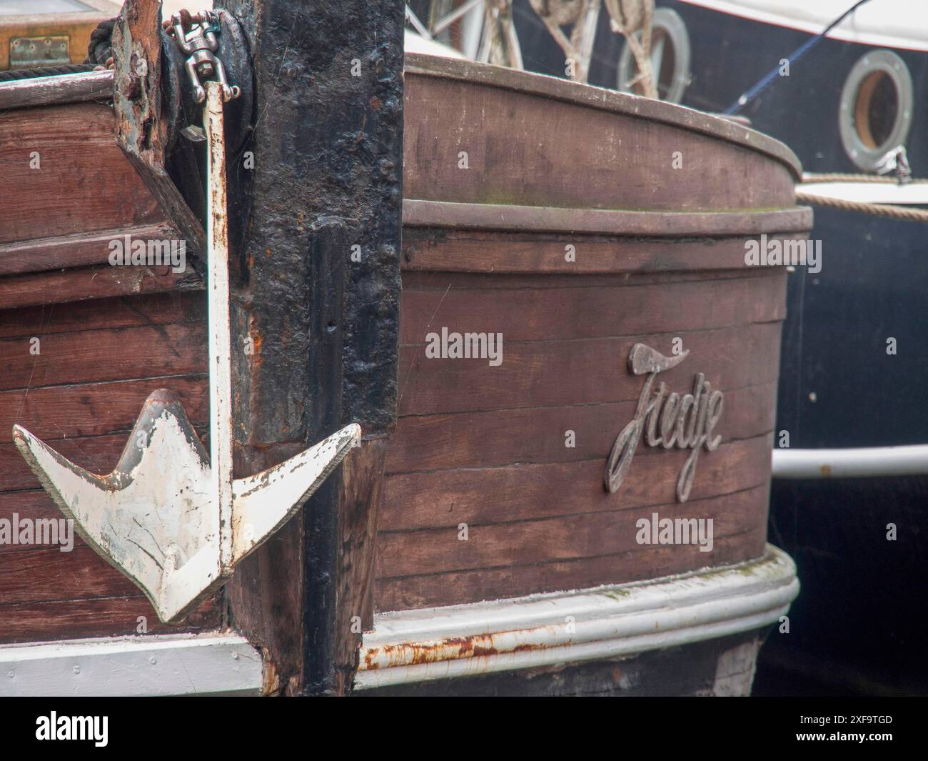 Old wooden boat with a rusty white anchor in the harbour, carolinensiel ...