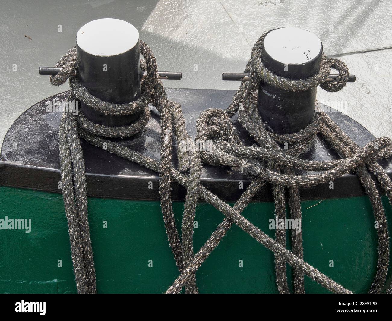 Close-up of two black metal bollards on a boat, surrounded by ropes and ...