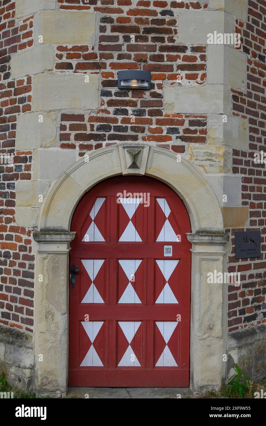 Historic red wooden door with white triangular patterns in a stone wall ...