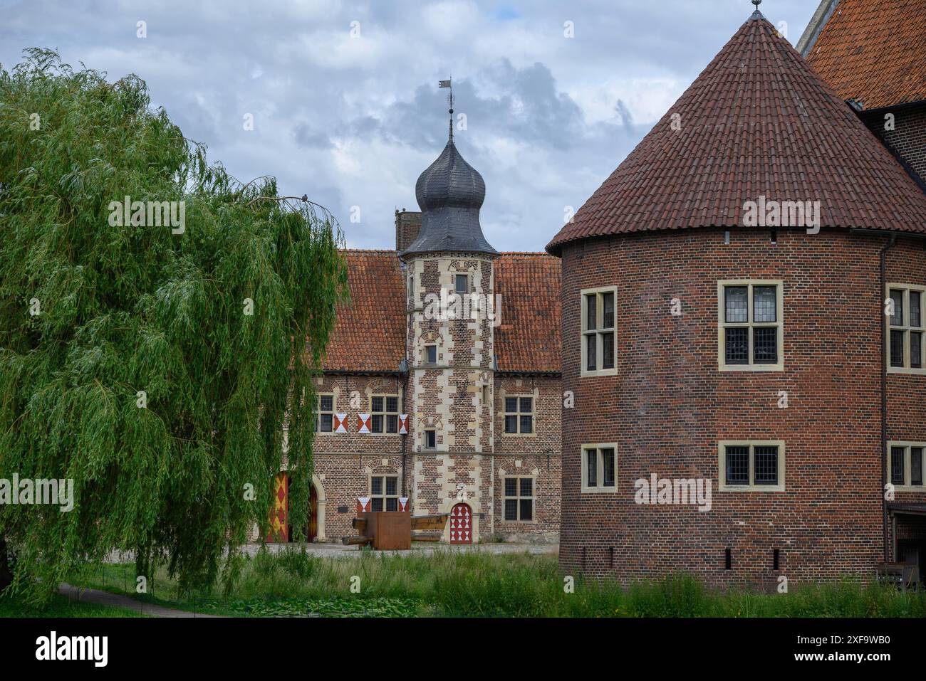 Historic castle with striking towers, red tiled roofs and a moat ...