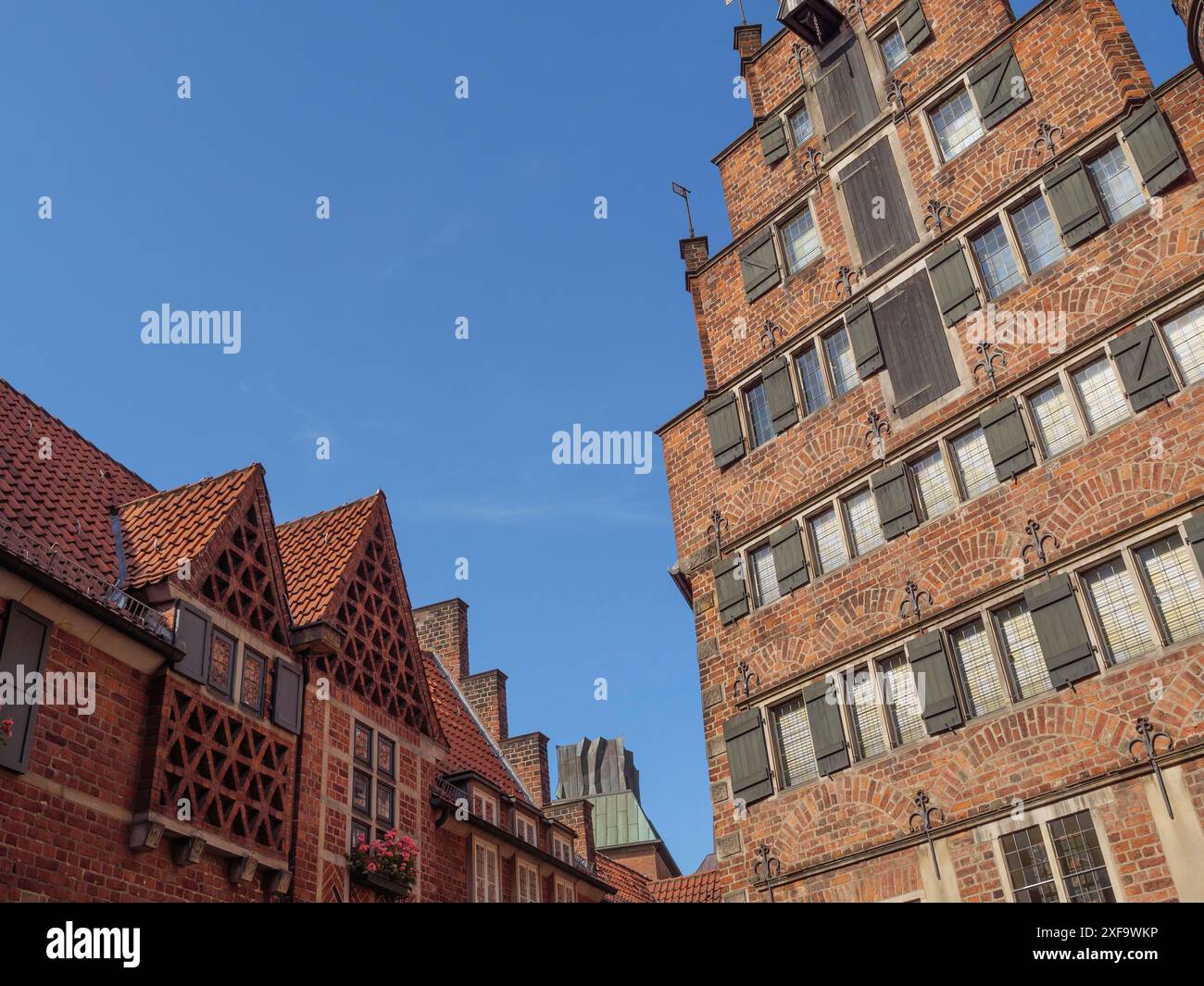 Two historic buildings with red brick facades and a clear blue sky in ...