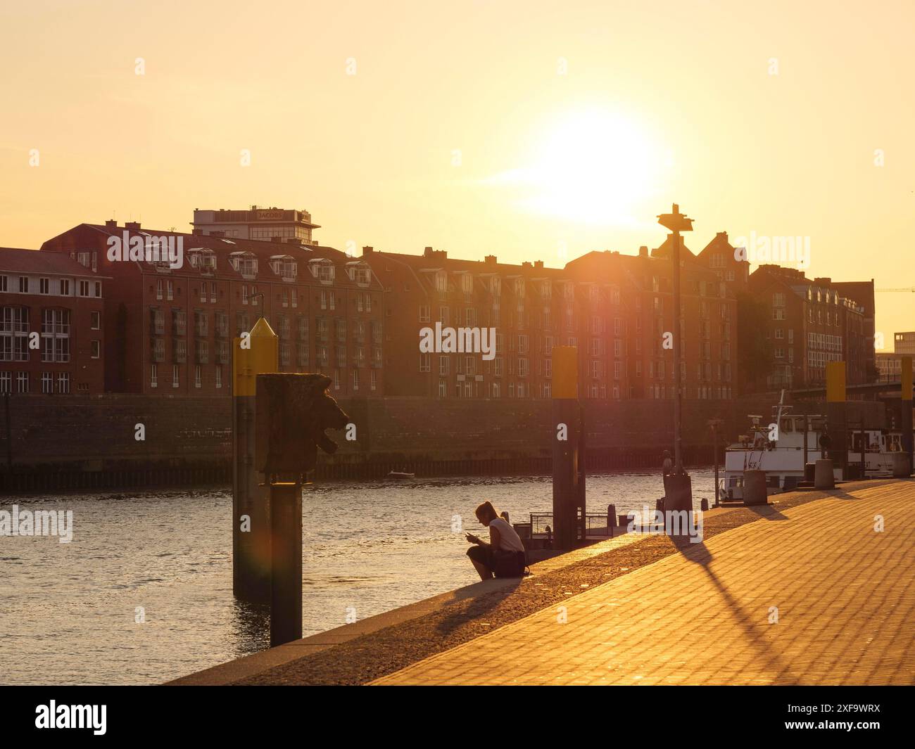 Waterfront promenade at sunset with warm colours, silhouettes of ...