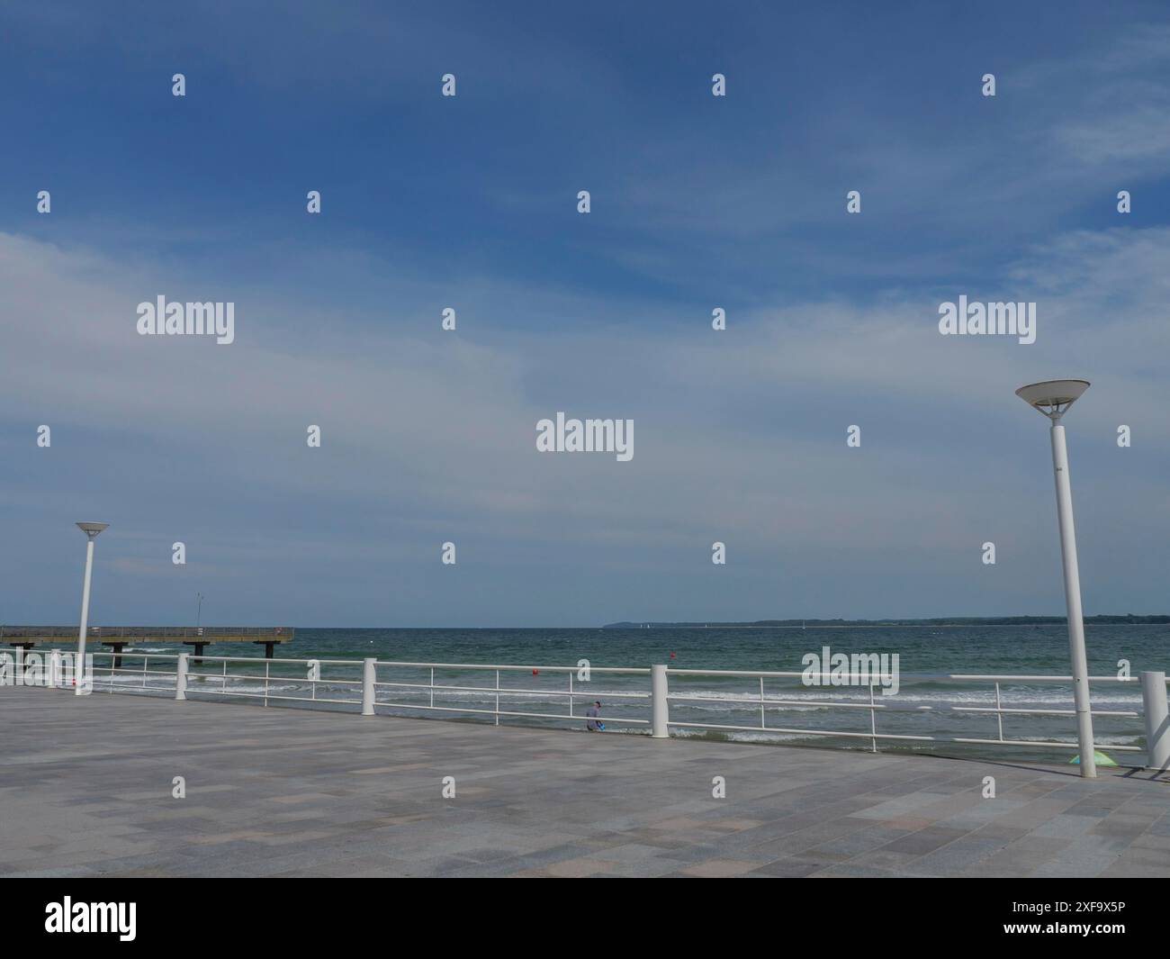 Promenade along the sea with white railings and lamps under a slightly ...
