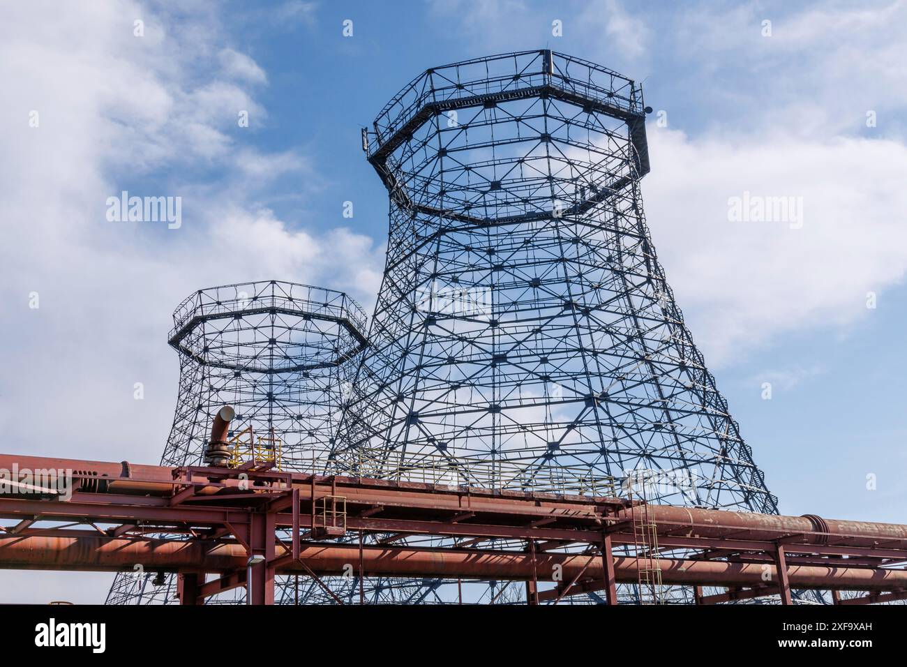 Two large cooling towers made of metal frame structures in front of a ...