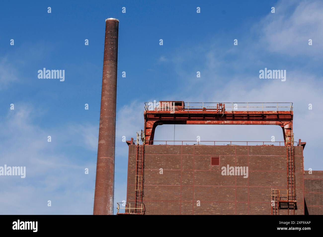 Brick industrial building with tall chimney and pale blue sky in the ...