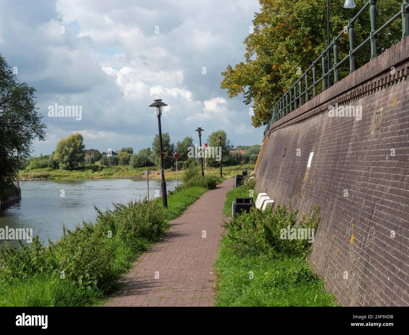Beautiful walkway along a river with lanterns and lush greenery along a ...