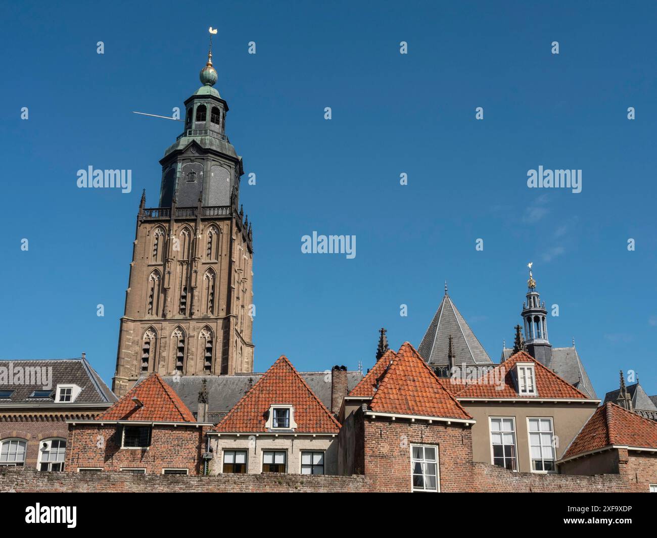 Old buildings with red roofs and a tall church tower under a bright ...