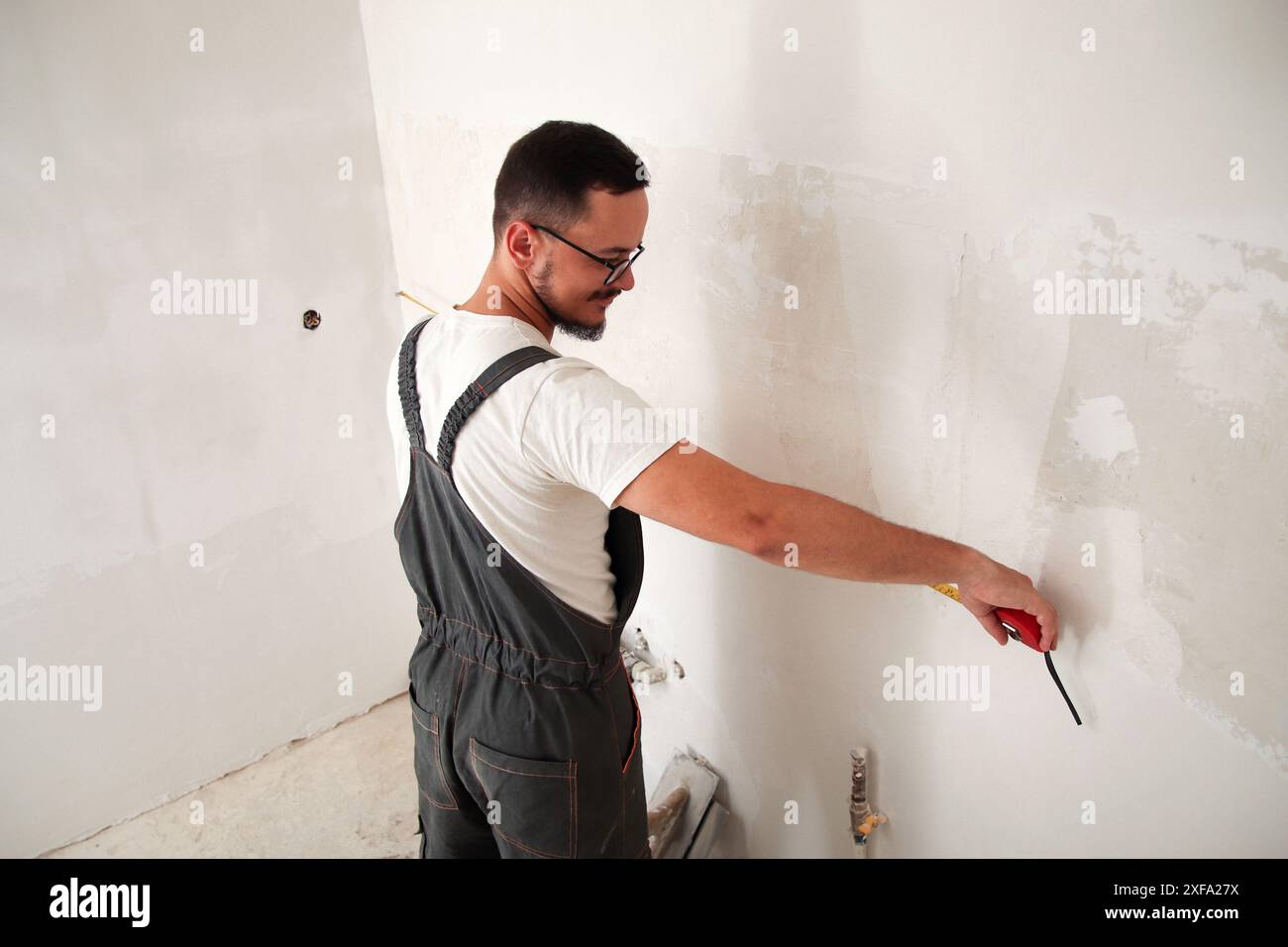 Construction worker measuring wall with tape measure, white background ...