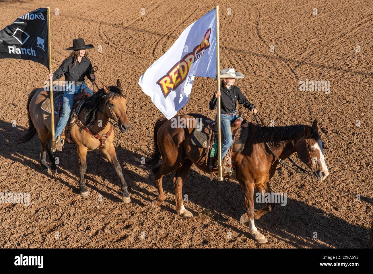 Young cowgirls carry the sponsors flags in the Grand Entry at a rodeo ...