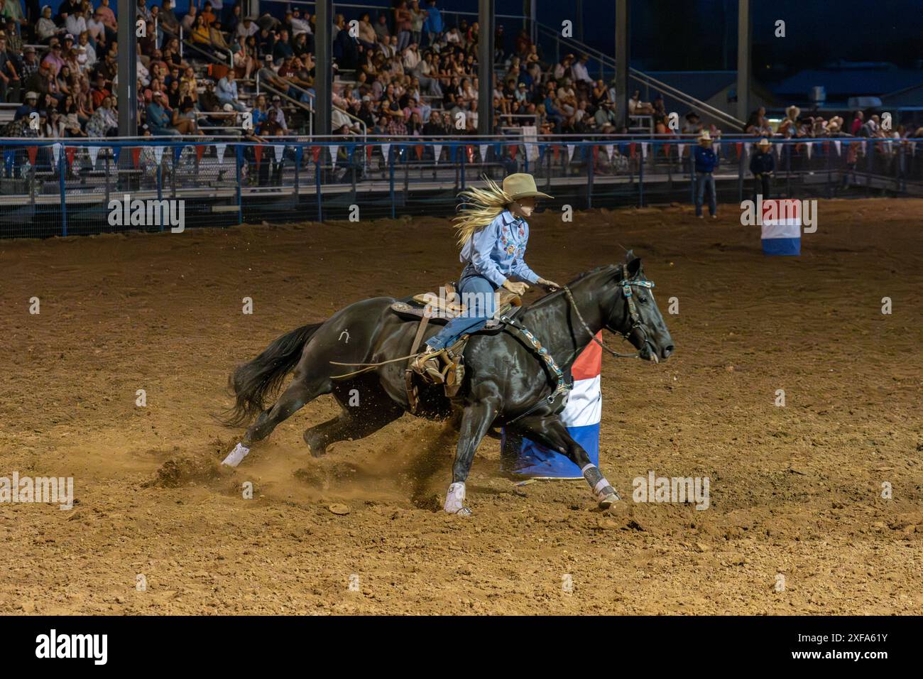 A cowgirl turns around the barrel while competing in the barrel racing ...