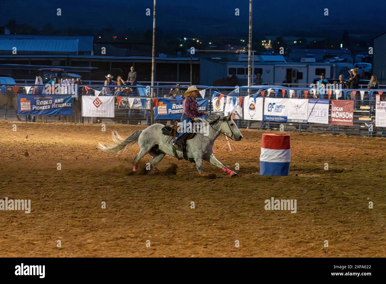 A cowgirl competing in the barrel racing event in a rodeo in rural Utah ...