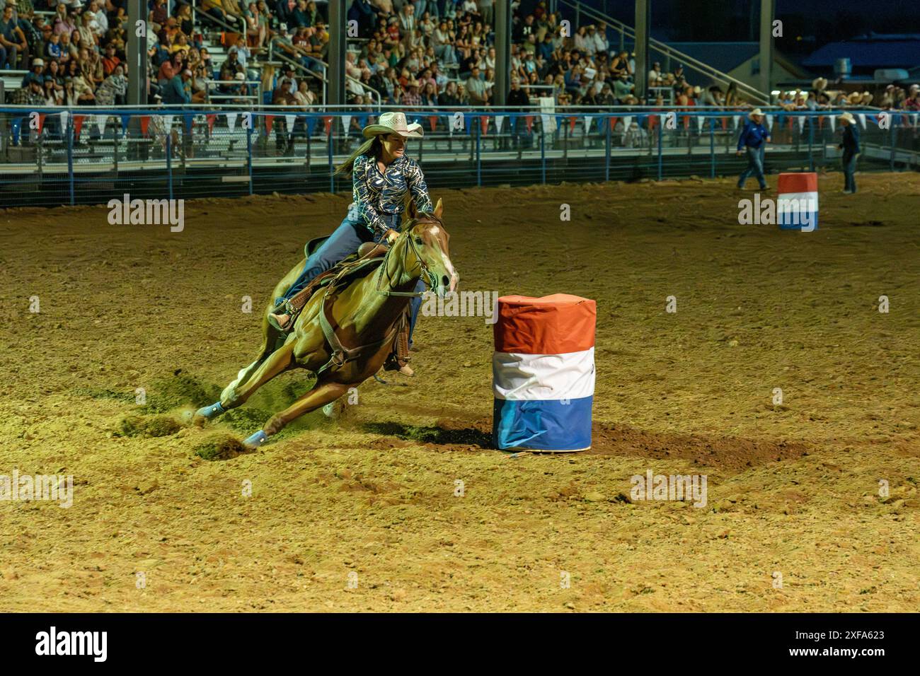 A cowgirl turns around the barrel while competing in the barrel racing ...