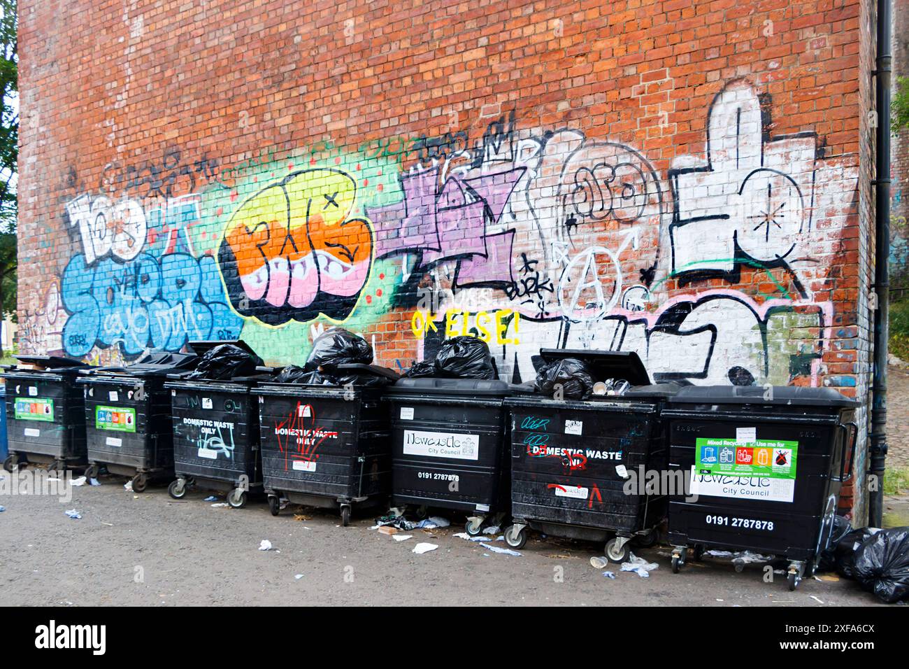 street art graffiti wall painting above row of commercial waste bins in ...