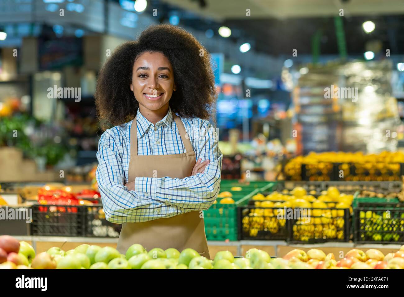 A cheerful grocery store employee with a big smile stands in front of ...