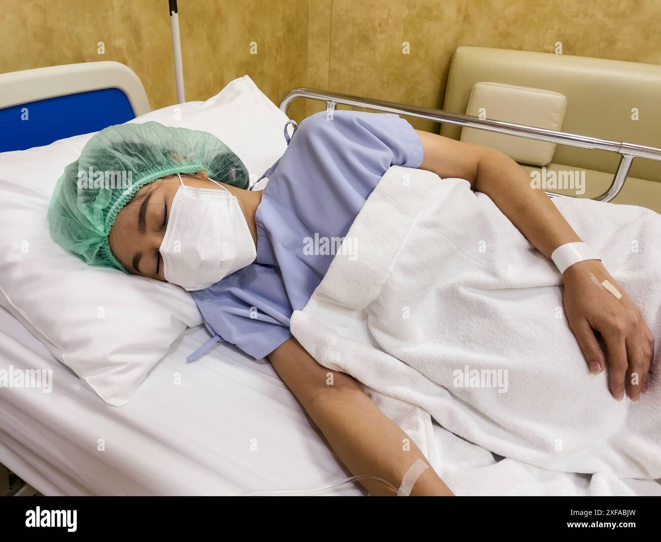 pregnant woman patient wearing medical mask while sleeping on a bed in ...