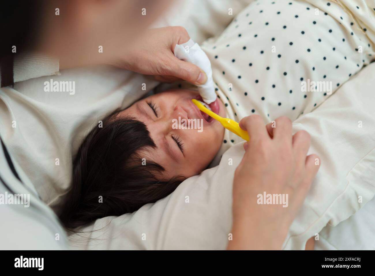 mother brushing her little daughters teeth. crying baby with tooth ...